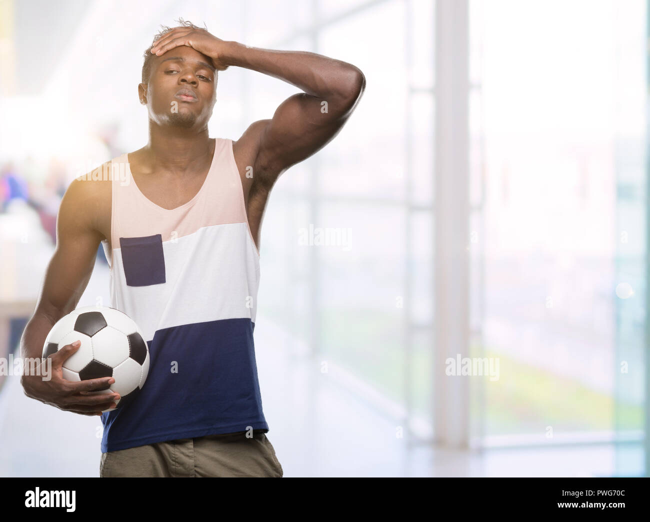 Young african american man holding soccer football ball stressed with ...