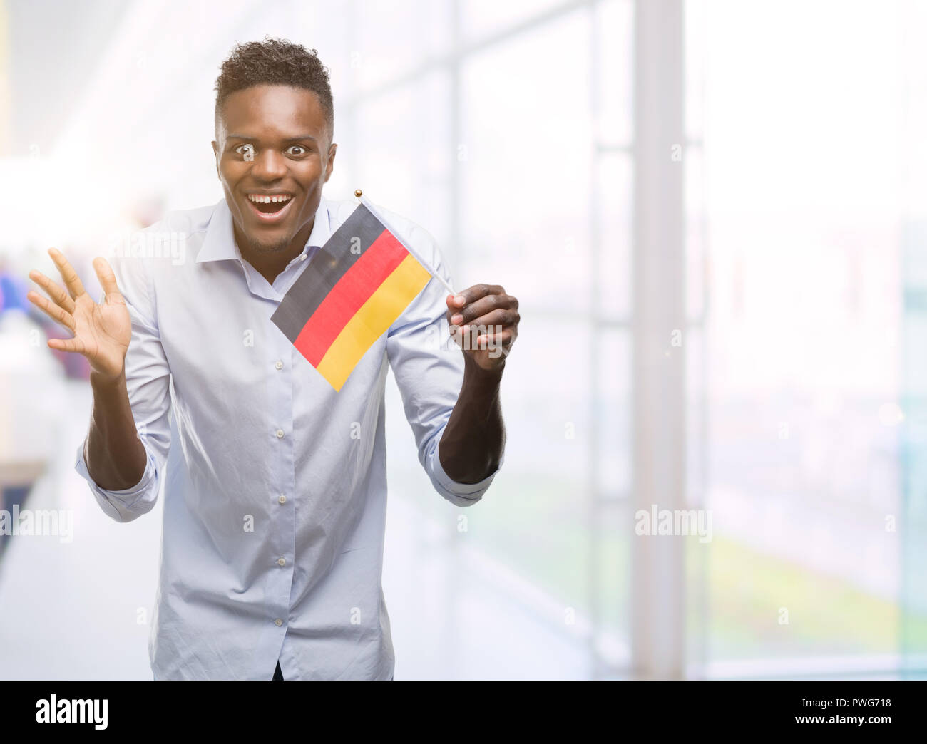 Young african american man holding german flag very happy and excited ...