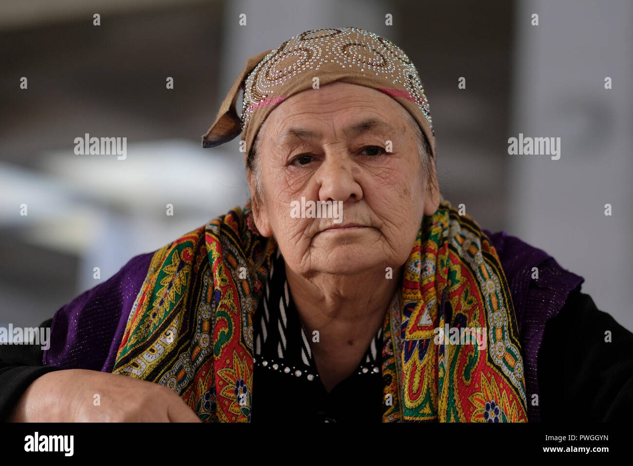 An elderly stall holder wearing traditional Uzbek garment in Siyob ...