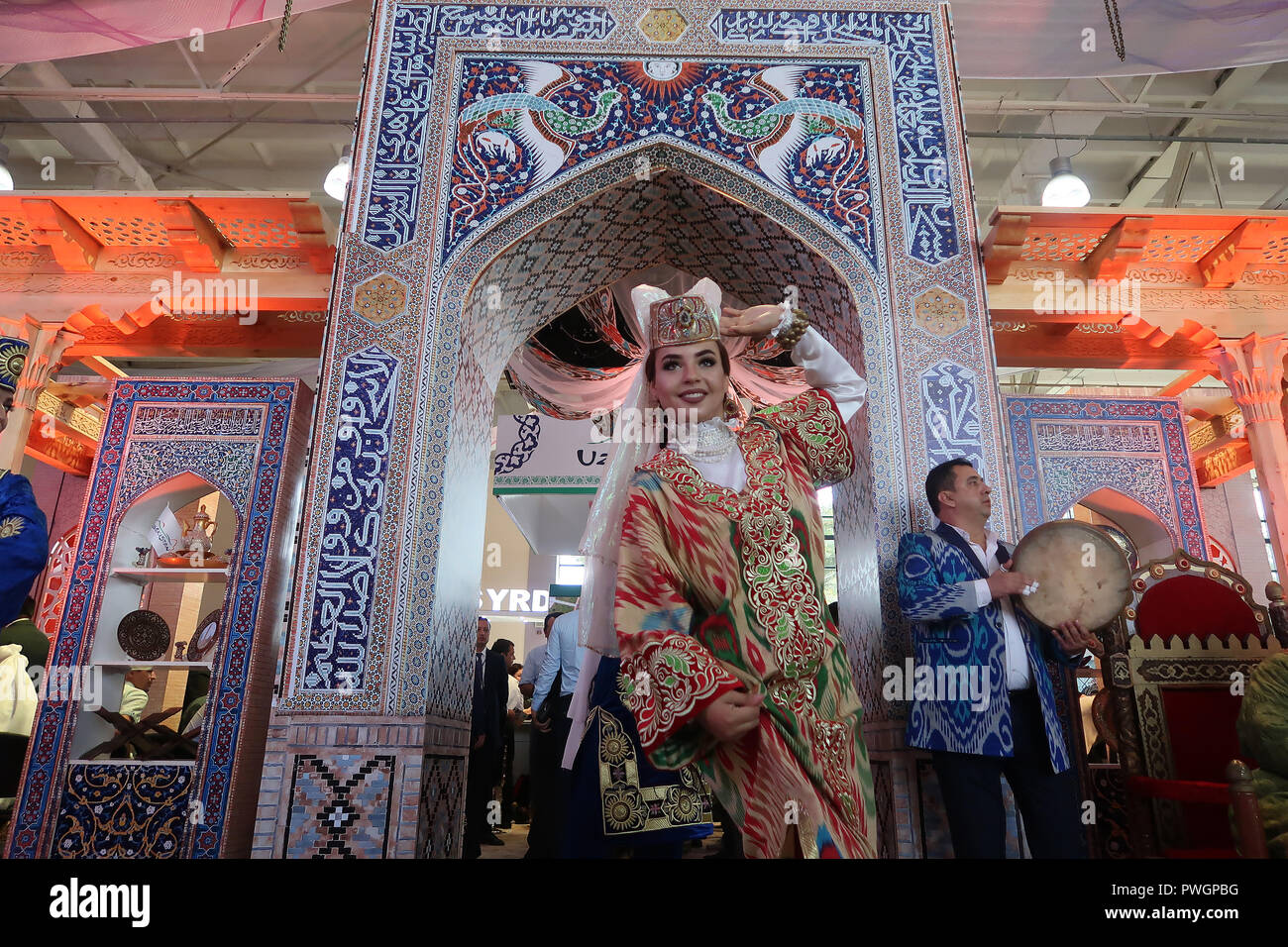 Young Uzbek woman wearing traditional satin fabric richly embroidered with golden thread dancing ...