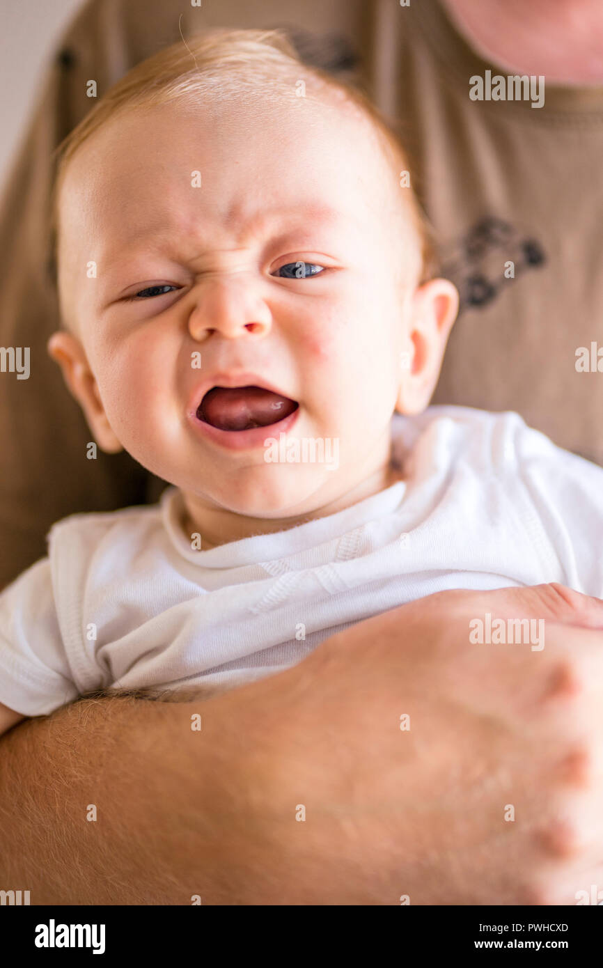 Father holding in right hand his crying, four months baby Stock Photo ...