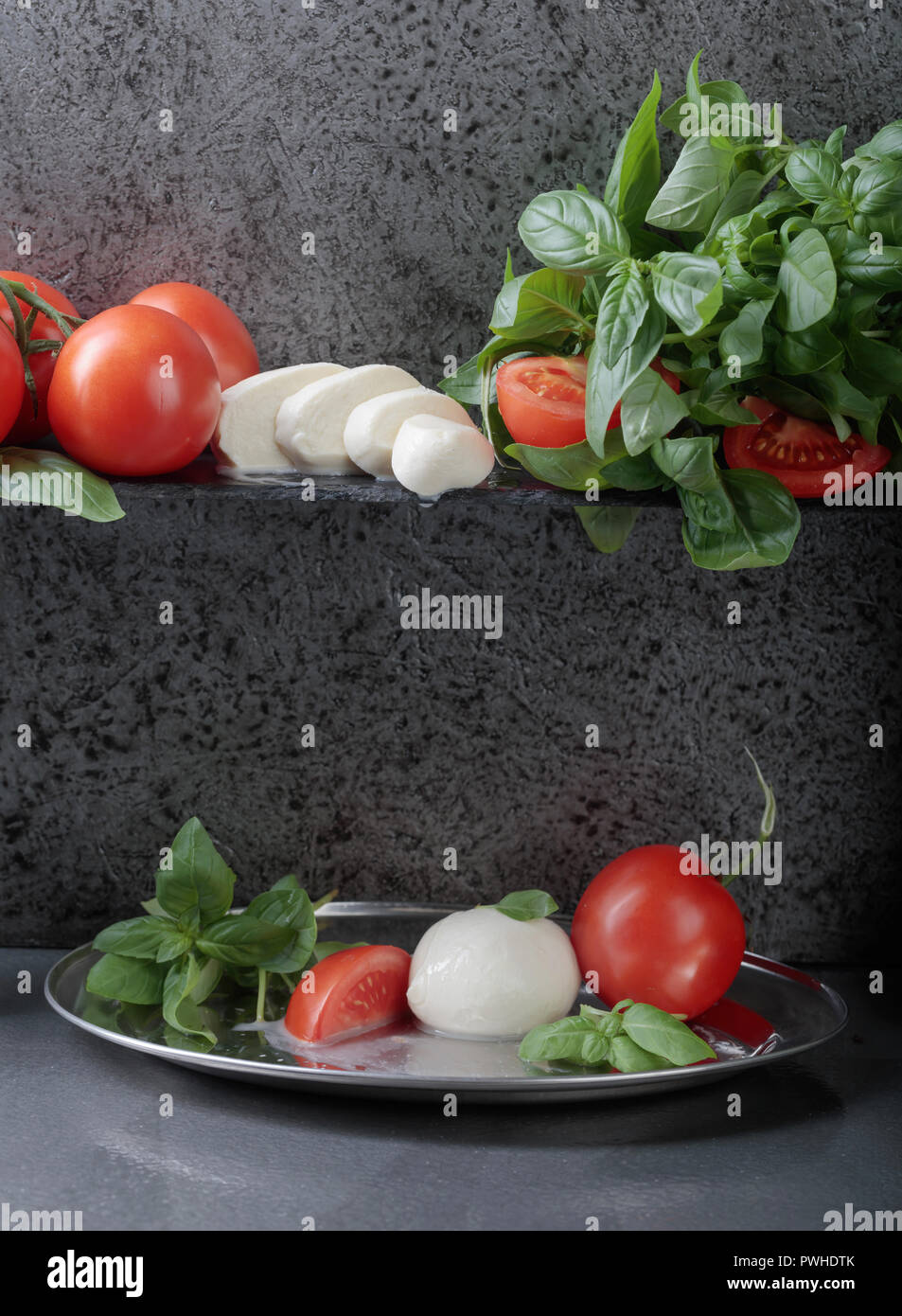 Mozzarella with basil and tomatoes on a background of old grey wall ...