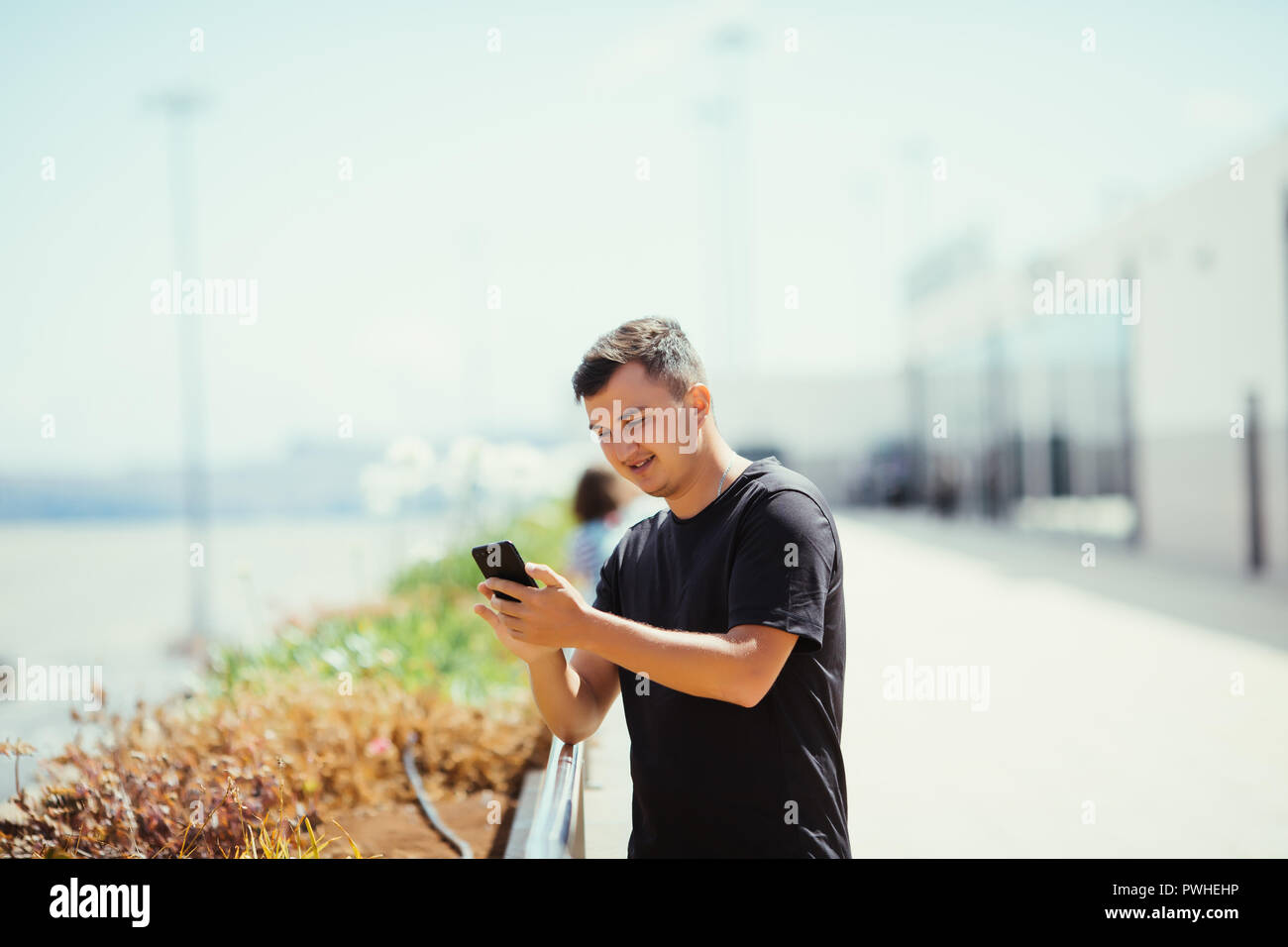 Young man use mobile phone in airport outdoors with plane on background ...