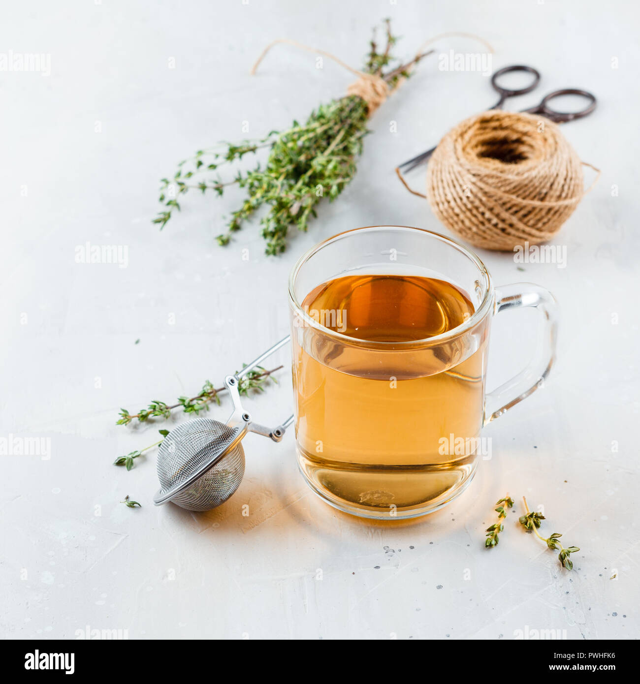 Transparent glass cup of herbal tea with thyme and sprigs of thyme tied ...