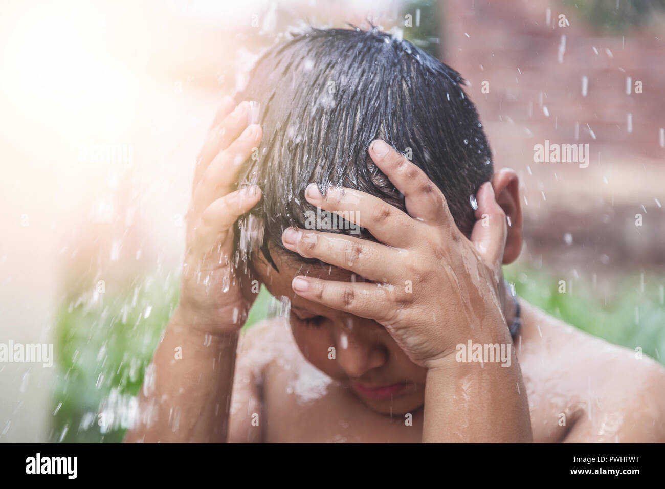 A child cooling down the heat with tap water during hot day in India ...