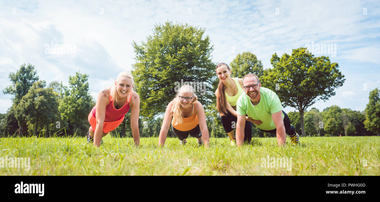 Family doing push-ups in nature under guidance by a fitness coac Stock ...