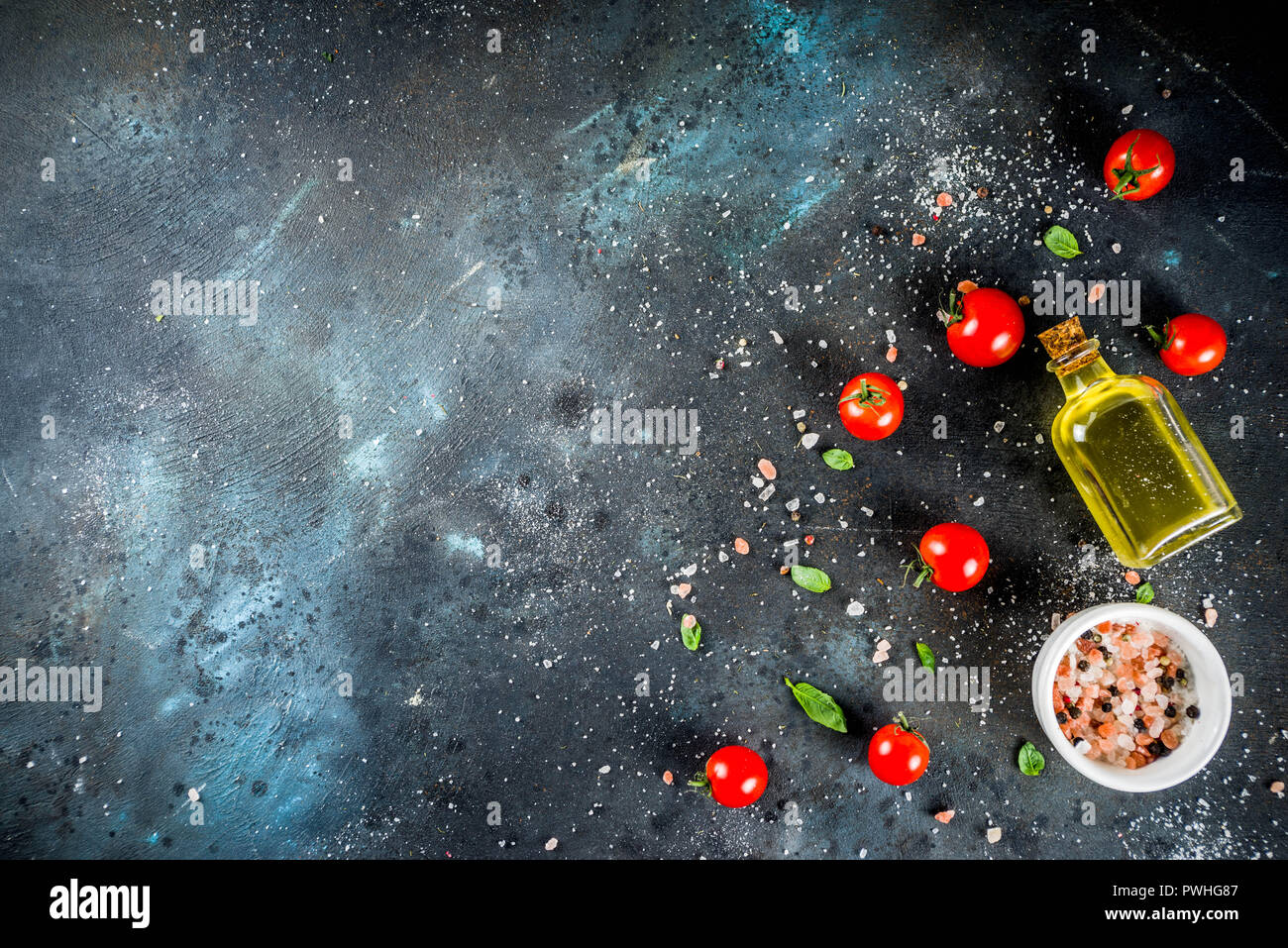 Dark cooking food background with salt, tomatoes and basil, top view ...