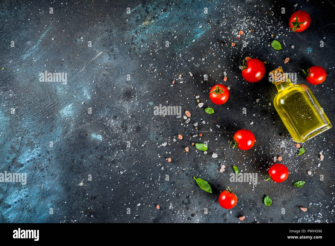 Dark cooking food background with salt, tomatoes and basil, top view ...