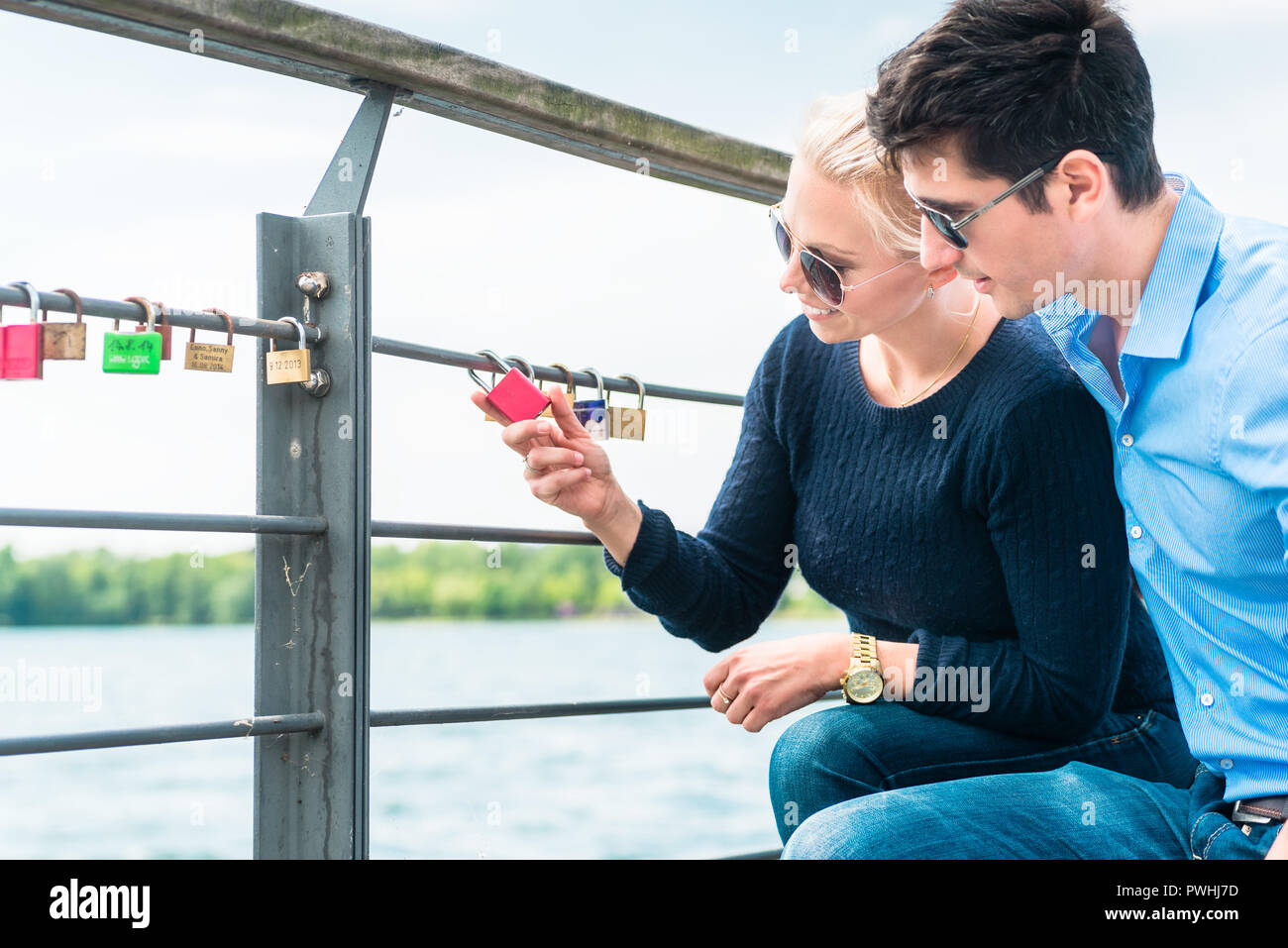 Young couple looking at padlock hang on railing Stock Photo - Alamy