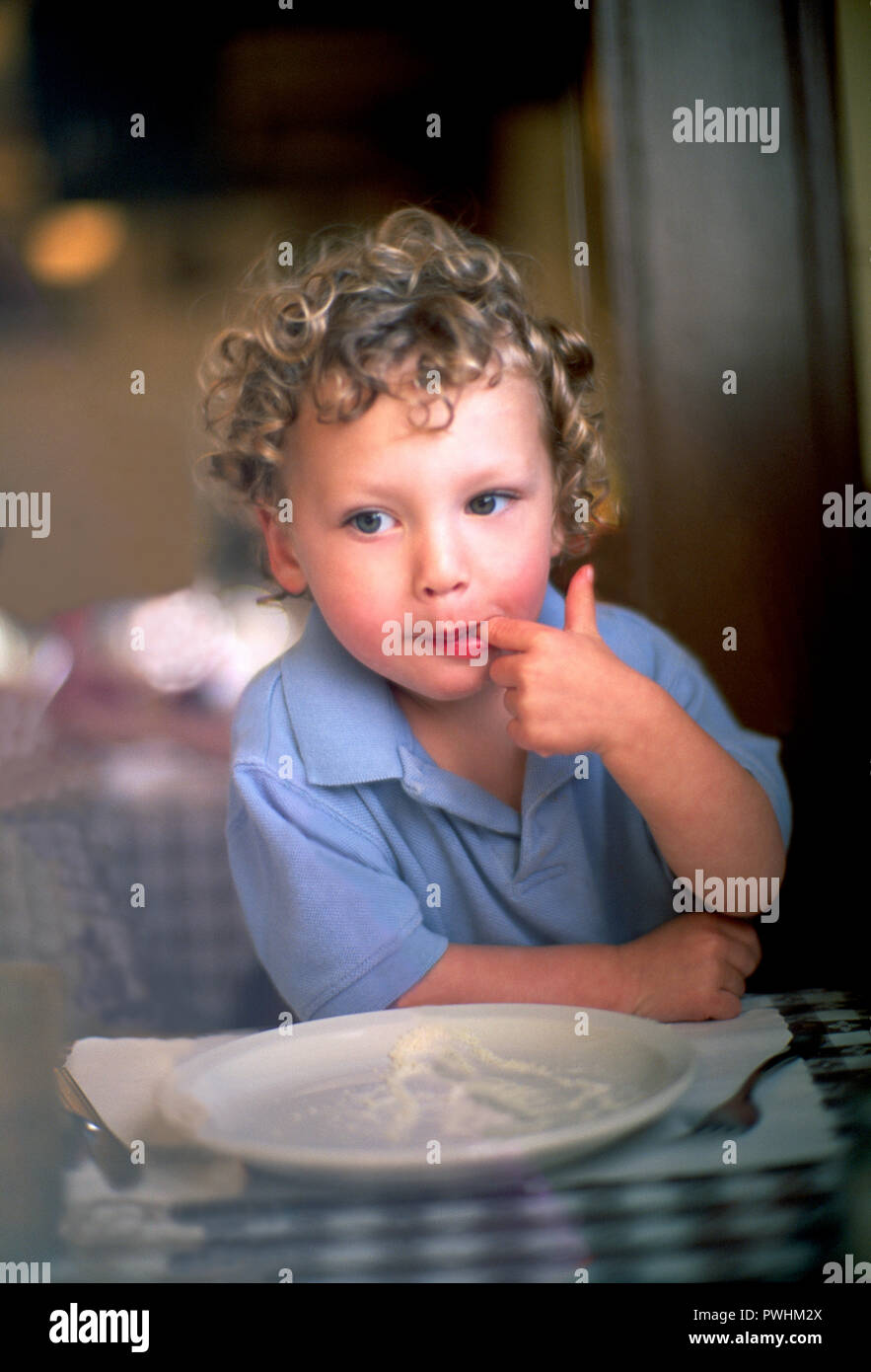 Little boy finishing his dinner at a restaurant Stock Photo - Alamy