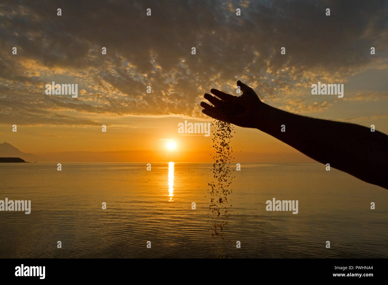 Life time passing concept. Man hand pour sand on the sunrise background ...