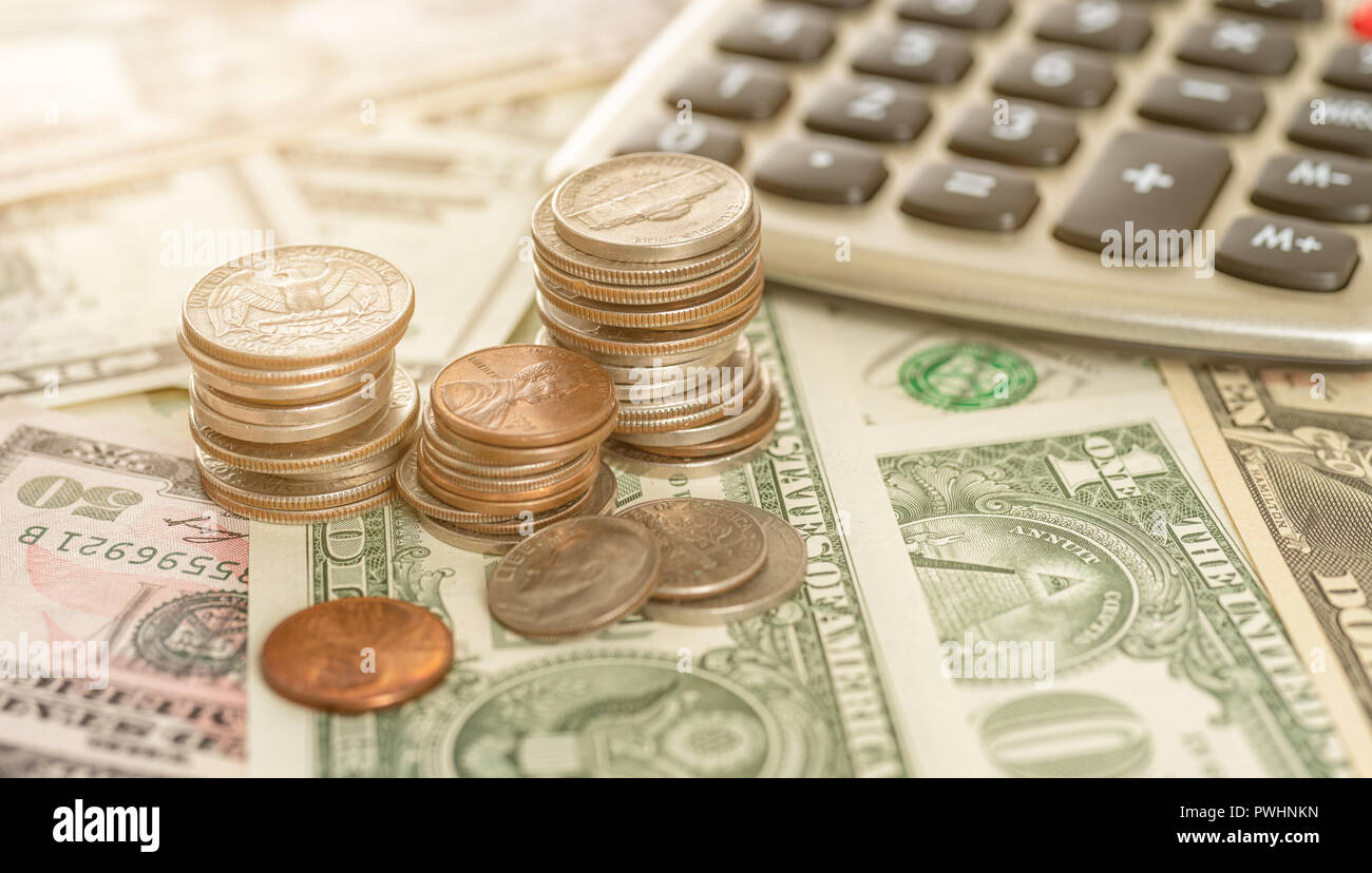 Coin stacks with dollar bills and a calculator Stock Photo - Alamy