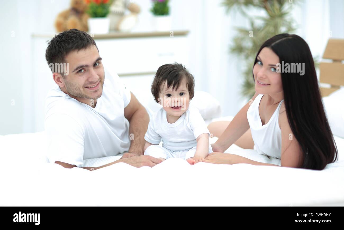 people, family and morning concept - happy child with parents waking up ...