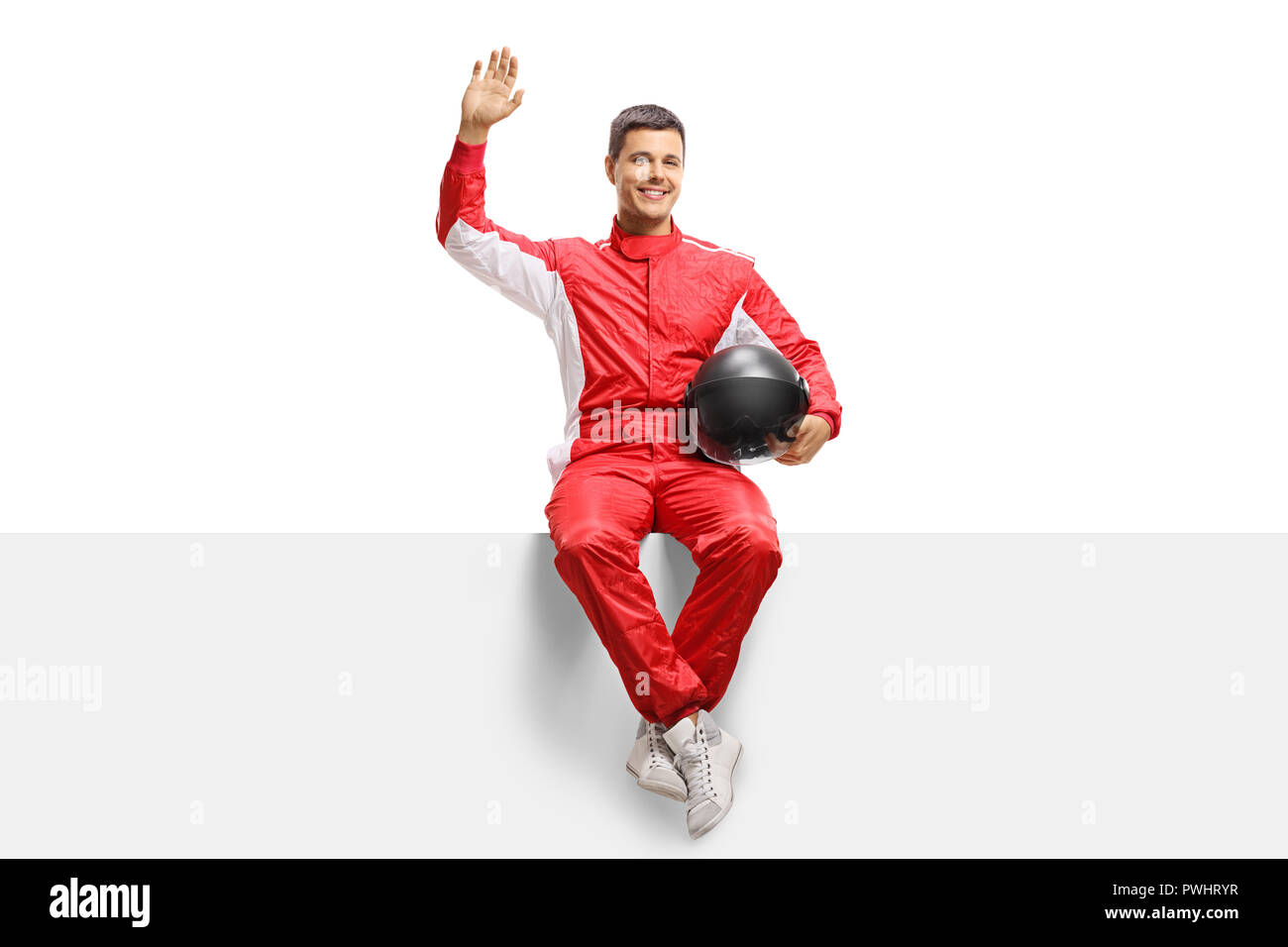 Race driver sitting on a panel and waving at the camera isolated on ...