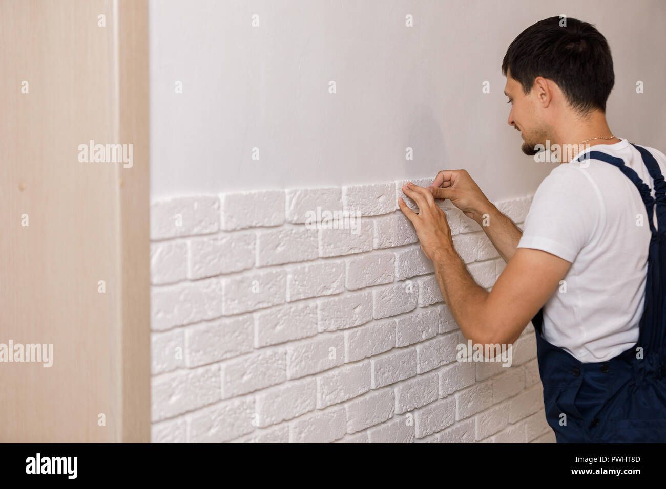 Professional Builder gluing decorative tile on wall Stock Photo - Alamy