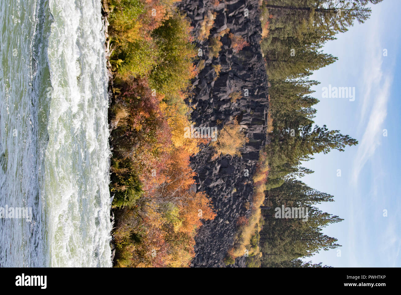 A talus slope gives way to bright fall foliage on the bank of the ...
