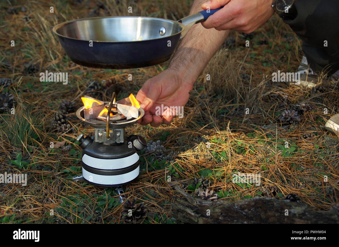 Flame under the pan in hand on the tourist stove. Starting the burner ...