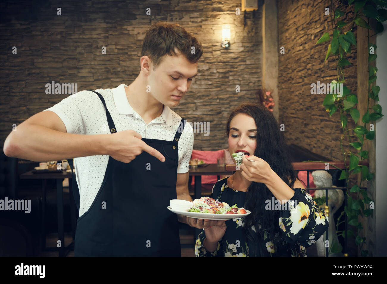 Handsome young waiter serving salad to customer Stock Photo - Alamy