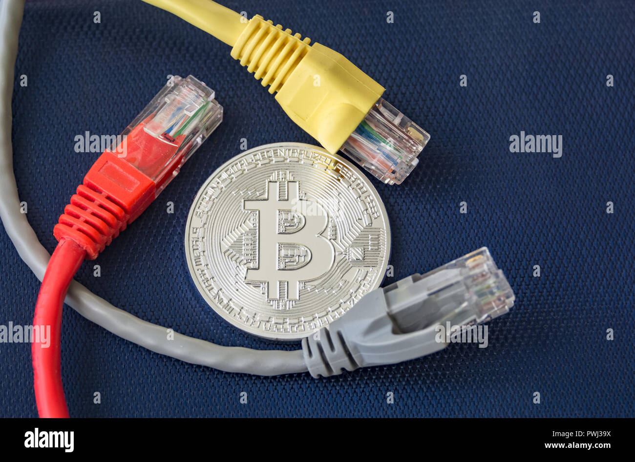 Metal coin of bitcoin with color ethernet plugs around Stock Photo - Alamy
