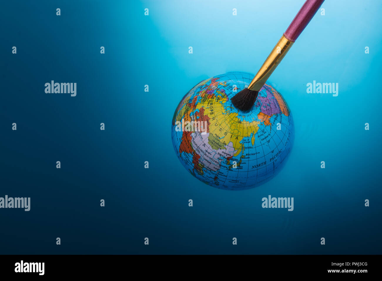 Brush and little globe with floating figurines around in water Stock ...
