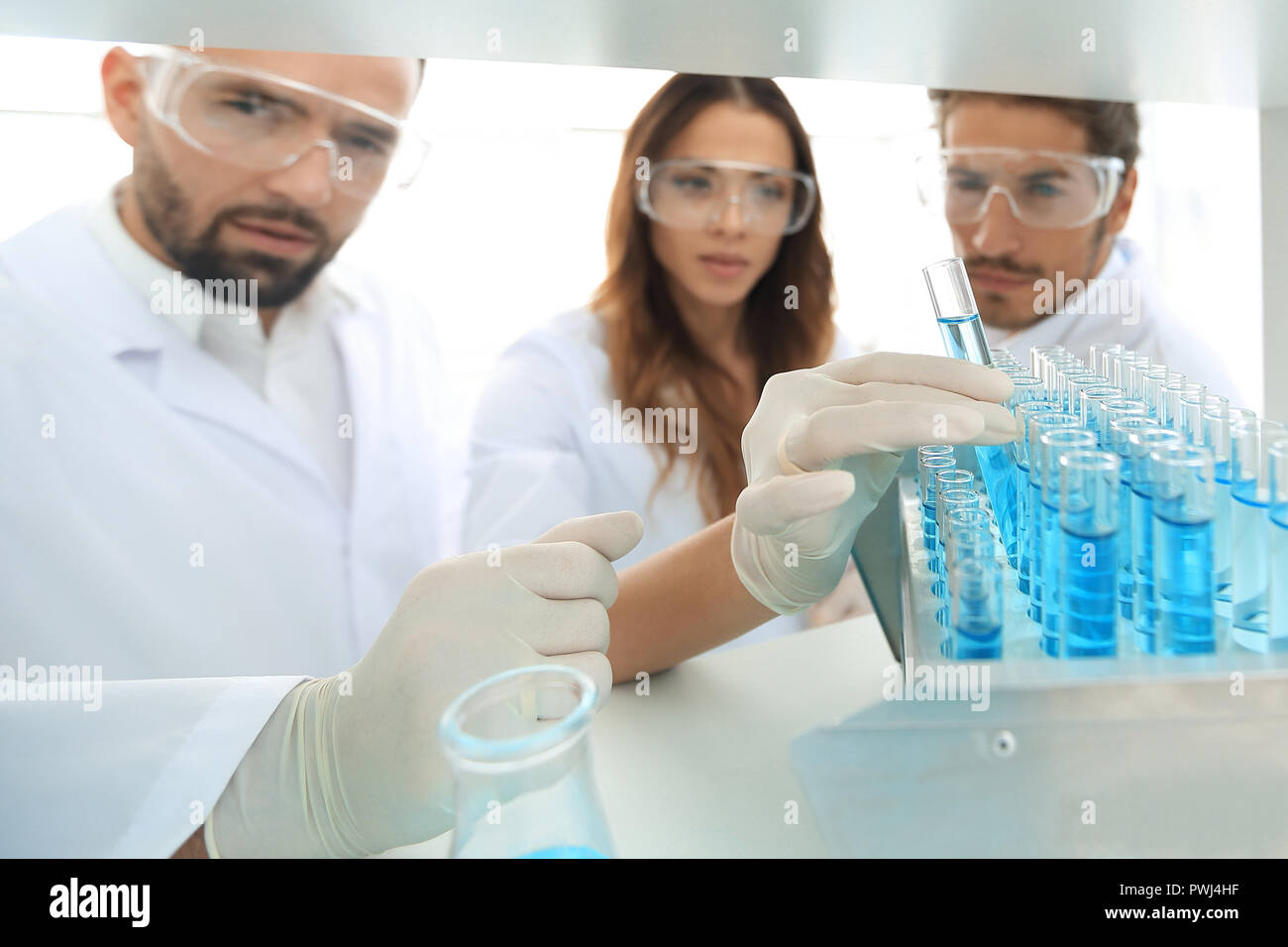 background image is a group of scientists studying the liquid in the ...
