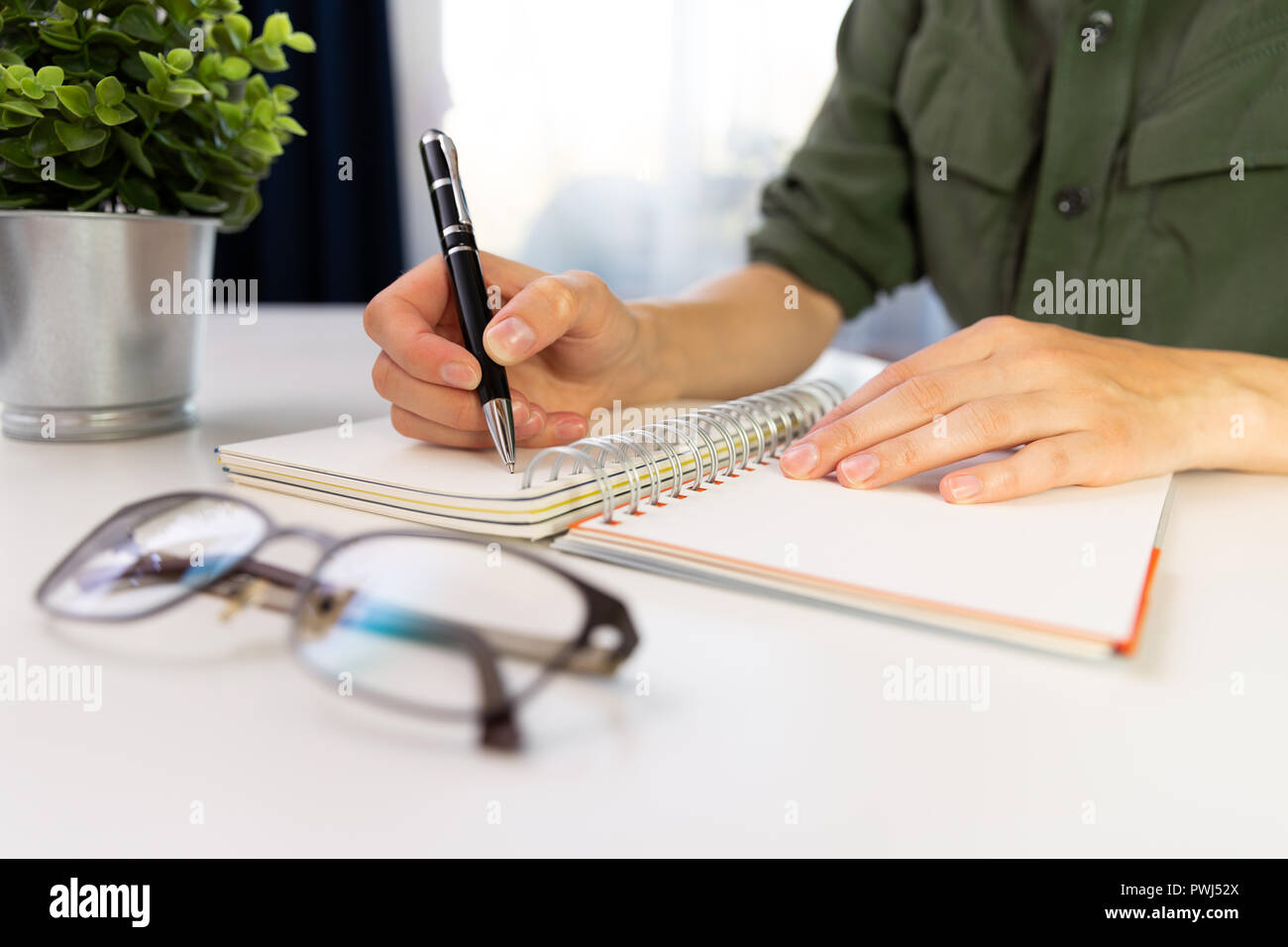 Woman's hands with pen writing on notebook. Modern office desk. Working ...