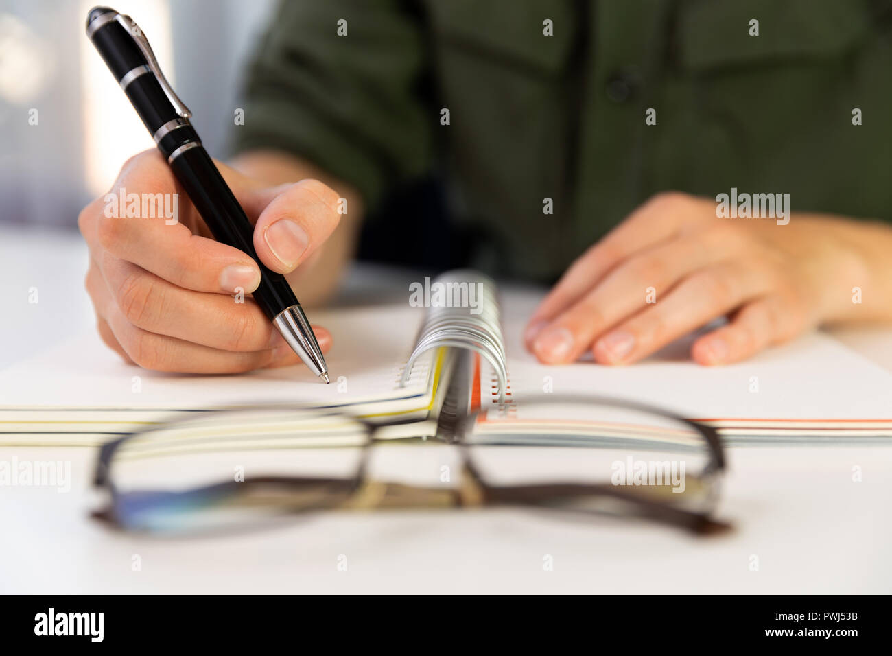 Woman's hands with pen writing on notebook. Modern office desk. Working ...