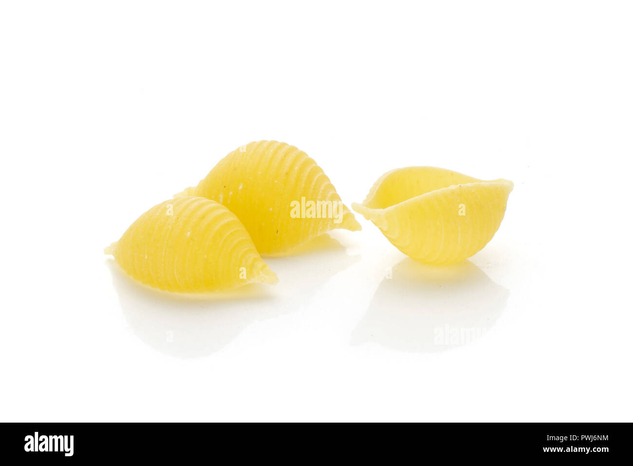 Group of three whole raw yellow pasta conchiglie variety like shells ...