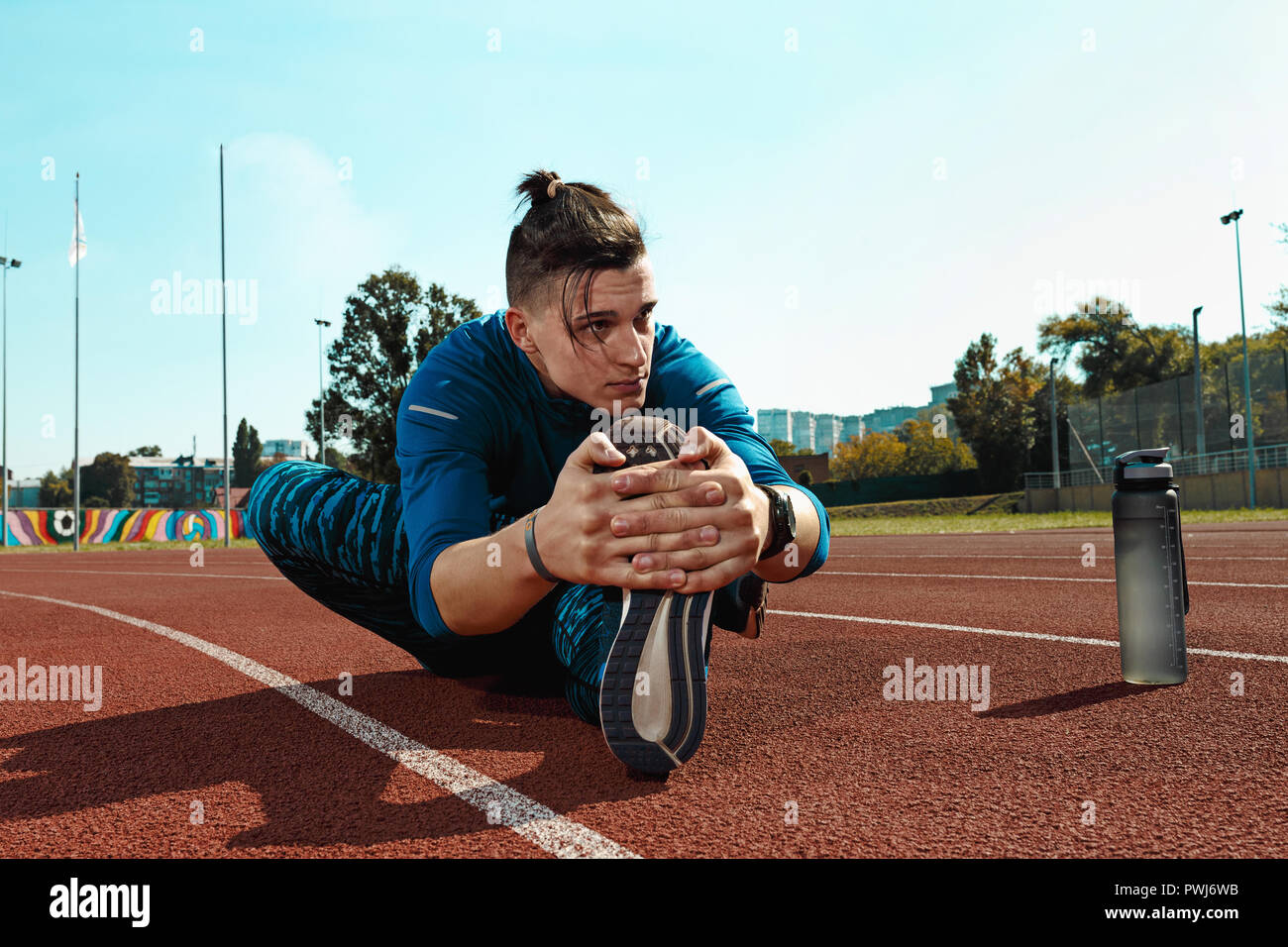 The fit male runner stretching legs preparing for run during training ...