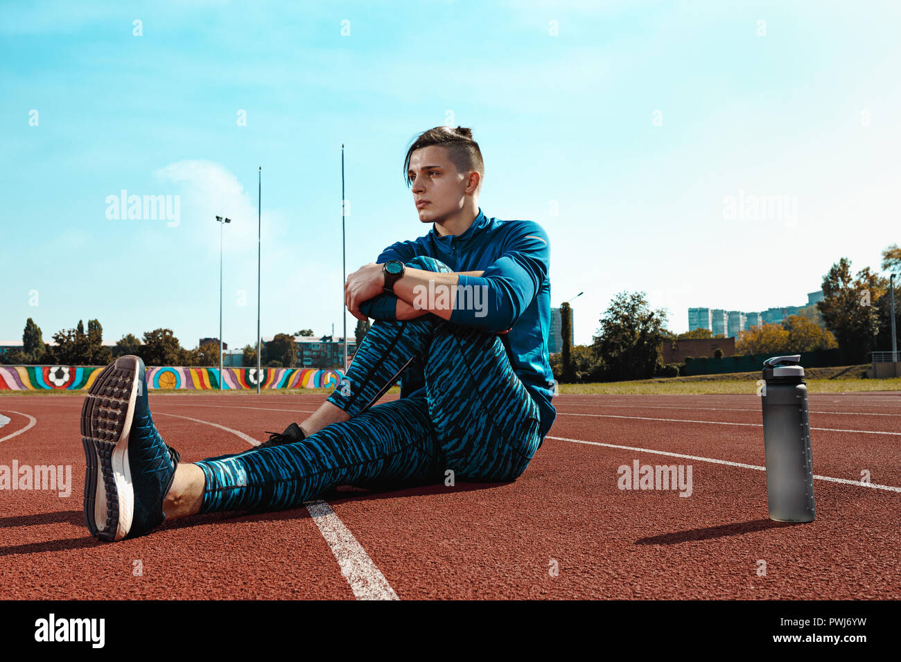 The fit male runner stretching legs preparing for run during training ...