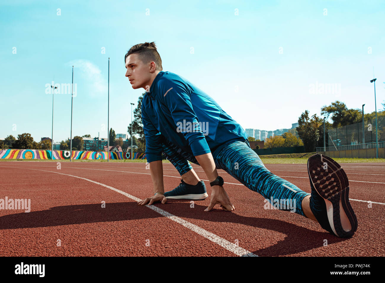 The fit male runner stretching legs preparing for run during training ...