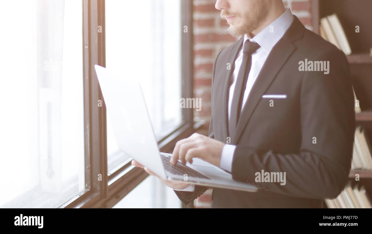 businessman typing on laptop while standing in office Stock Photo - Alamy