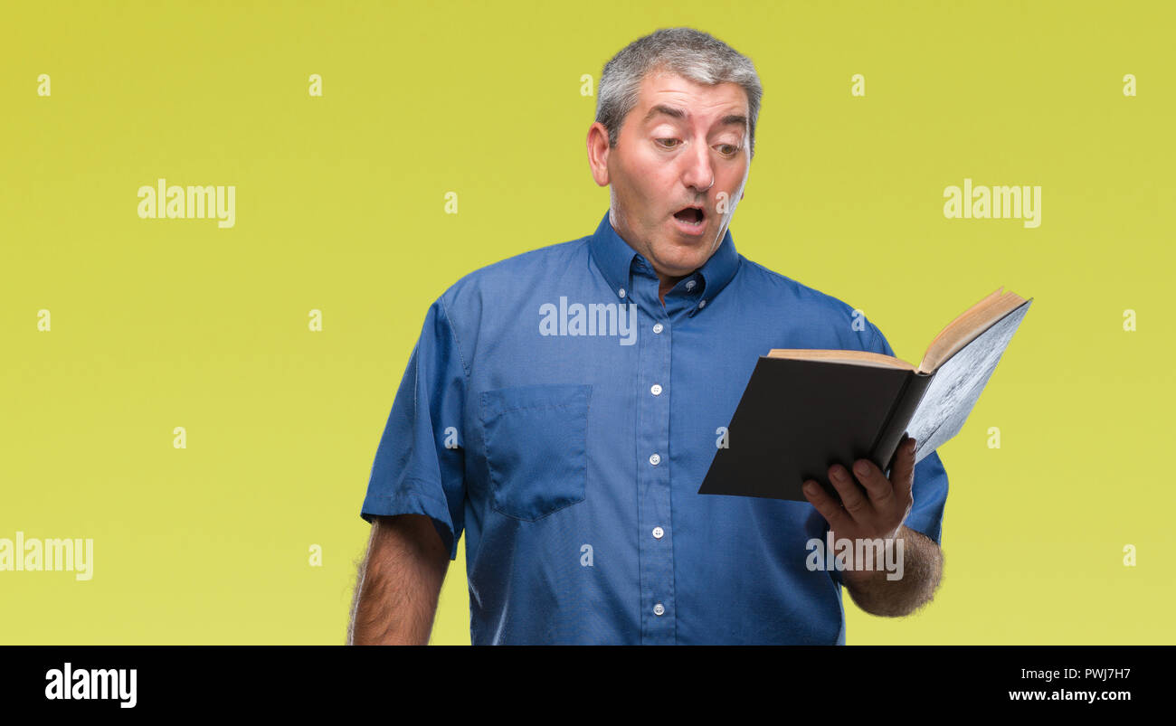 Handsome senior teacher man reading a book over isolated background ...