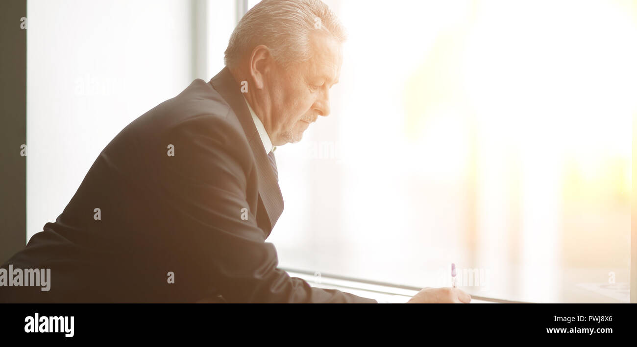 businessman signs a document, standing near the office window Stock ...