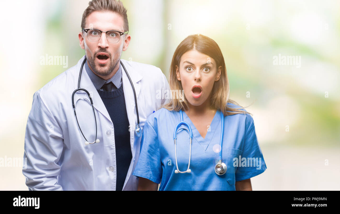 Young couple of doctor and surgeon over isolated background afraid and ...