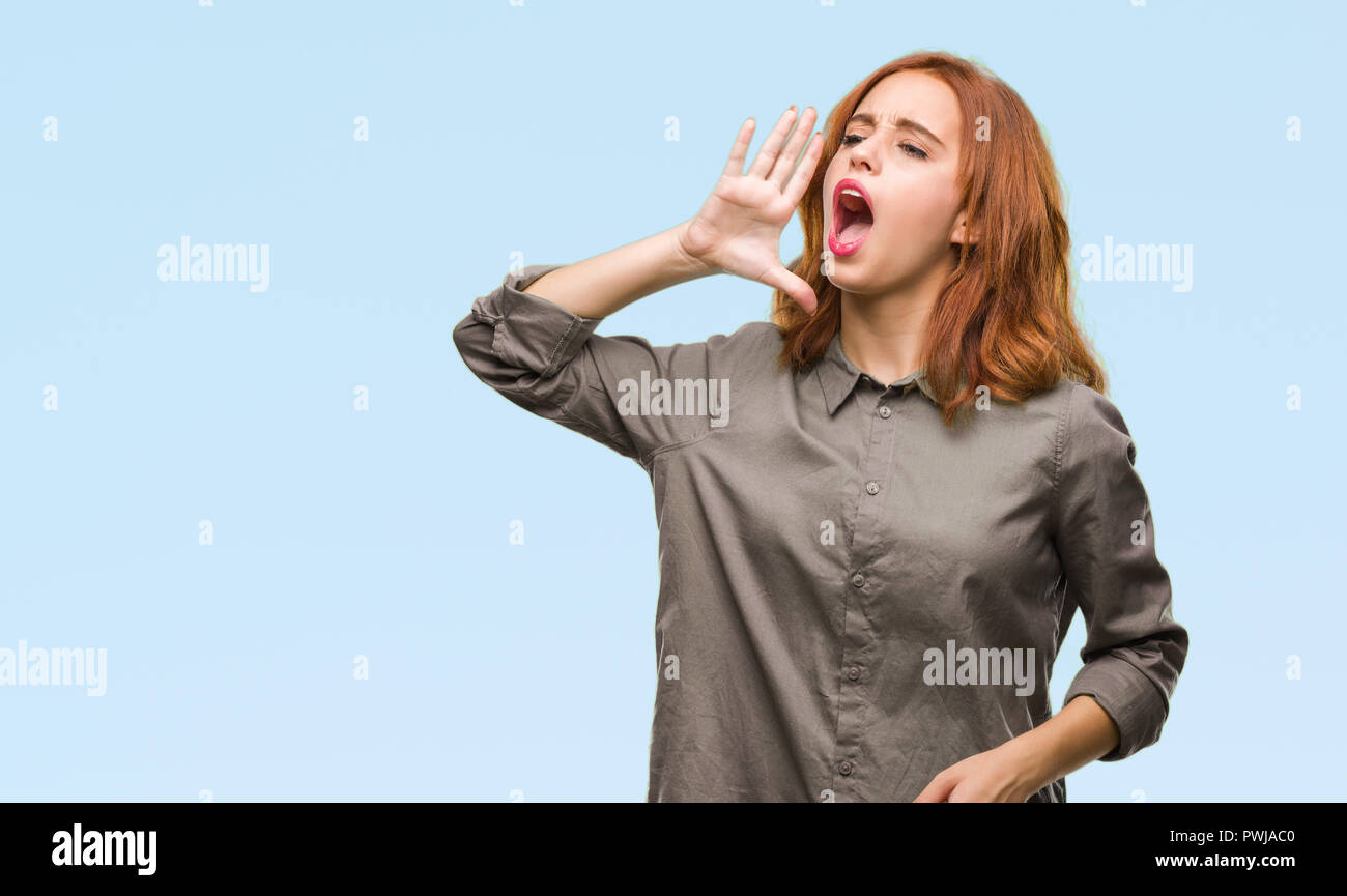 Young beautiful woman over isolated background shouting and screaming ...