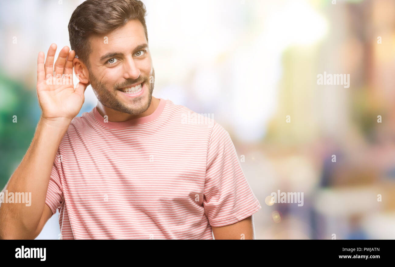 Young handsome man over isolated background smiling with hand over ear ...