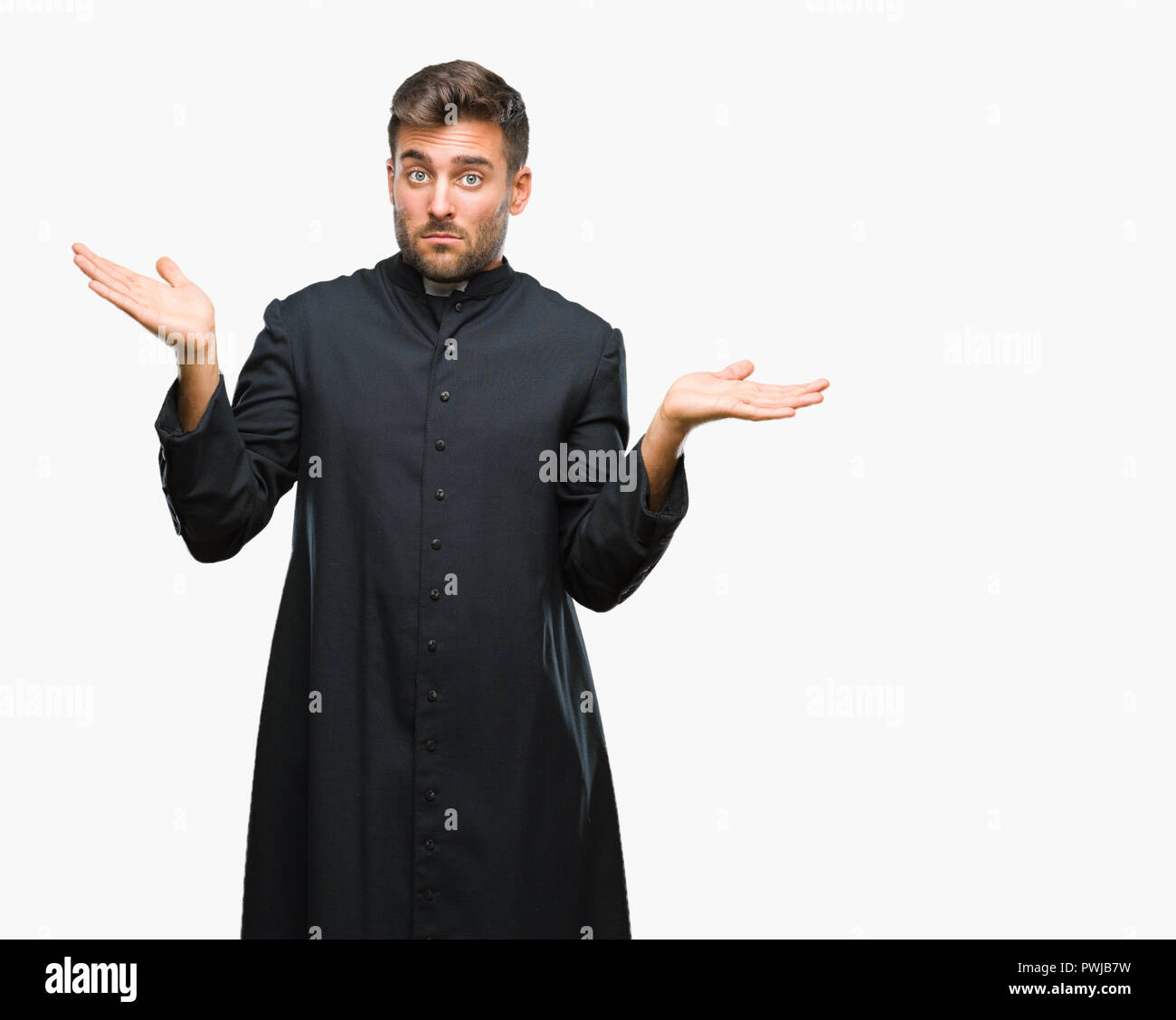 Young catholic christian priest man over isolated background clueless ...