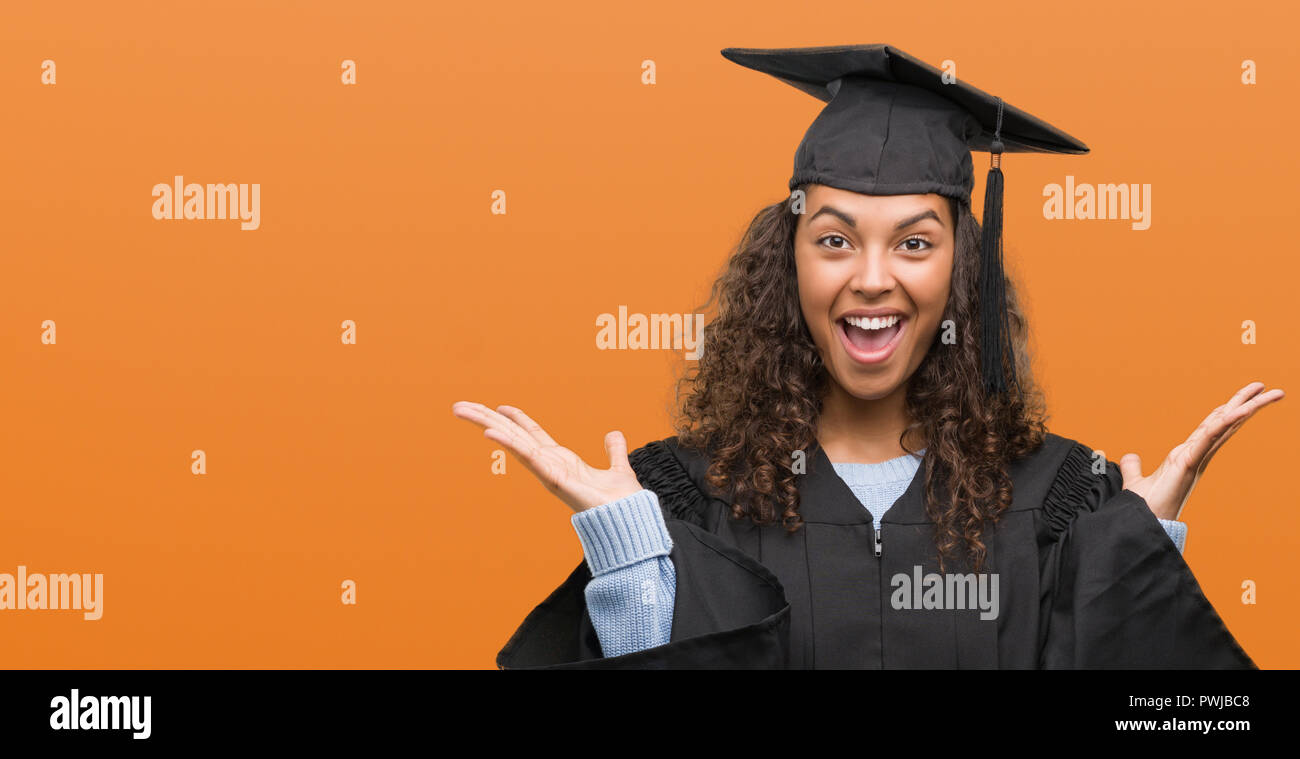 Young hispanic woman wearing graduation uniform very happy and excited ...