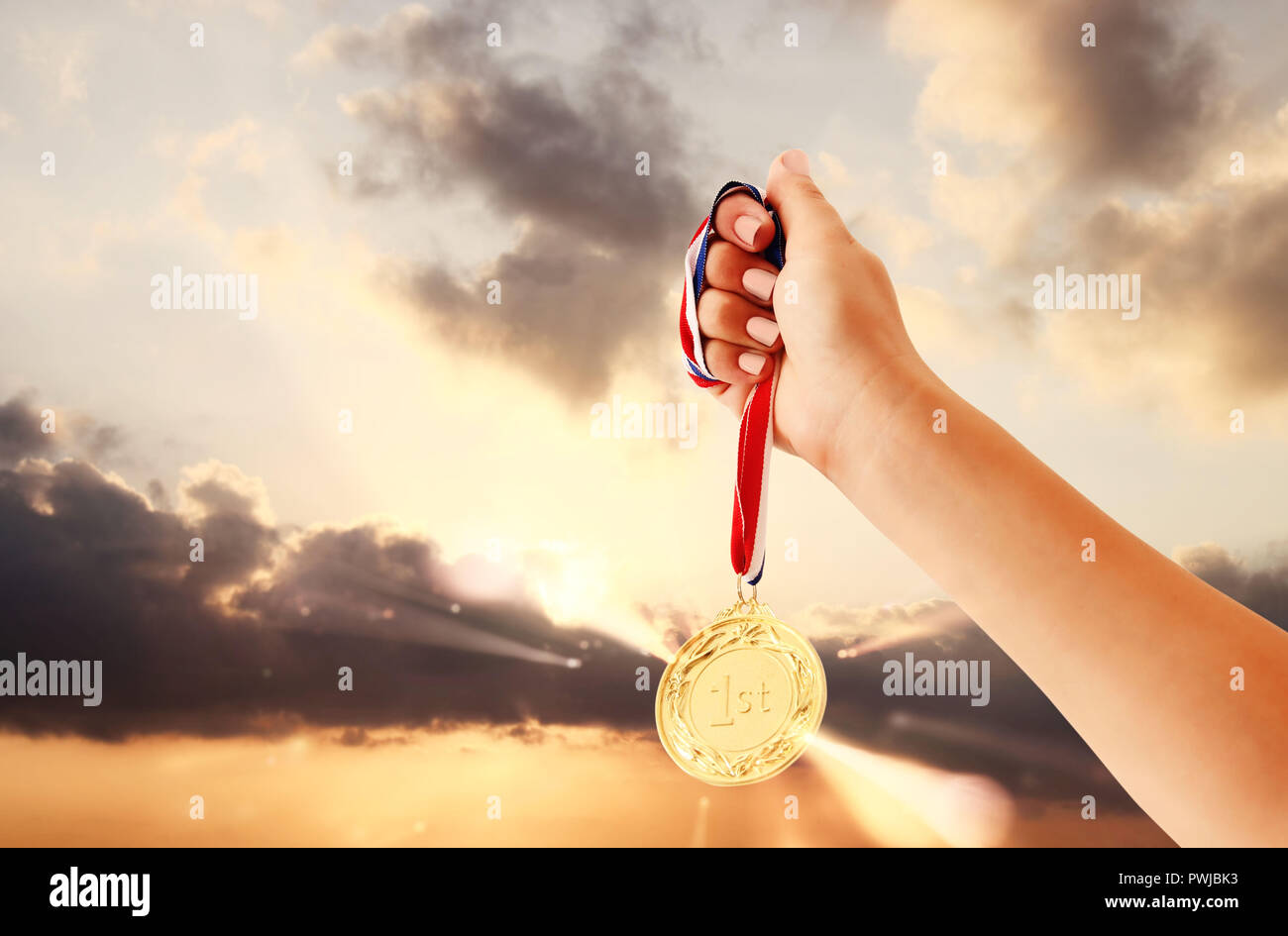 woman hand raised, holding gold medal against sky. award and victory ...