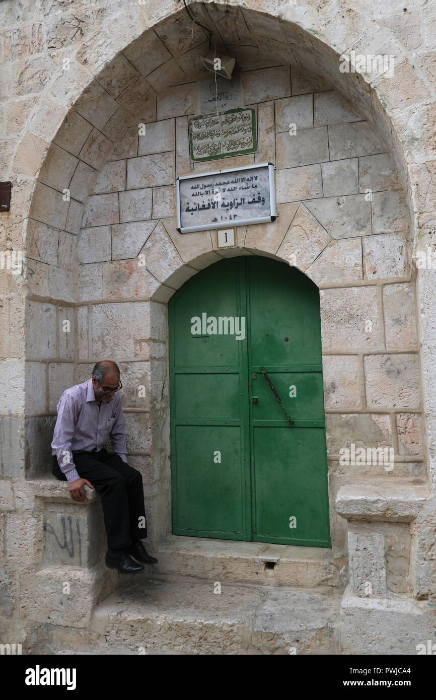 A Palestinian man sitting at the entrance to Al-Zawiya al-Qadiriyya ...