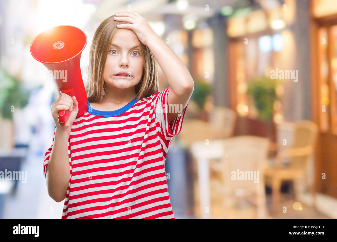 Young beautiful girl yelling through megaphone over isolated background ...