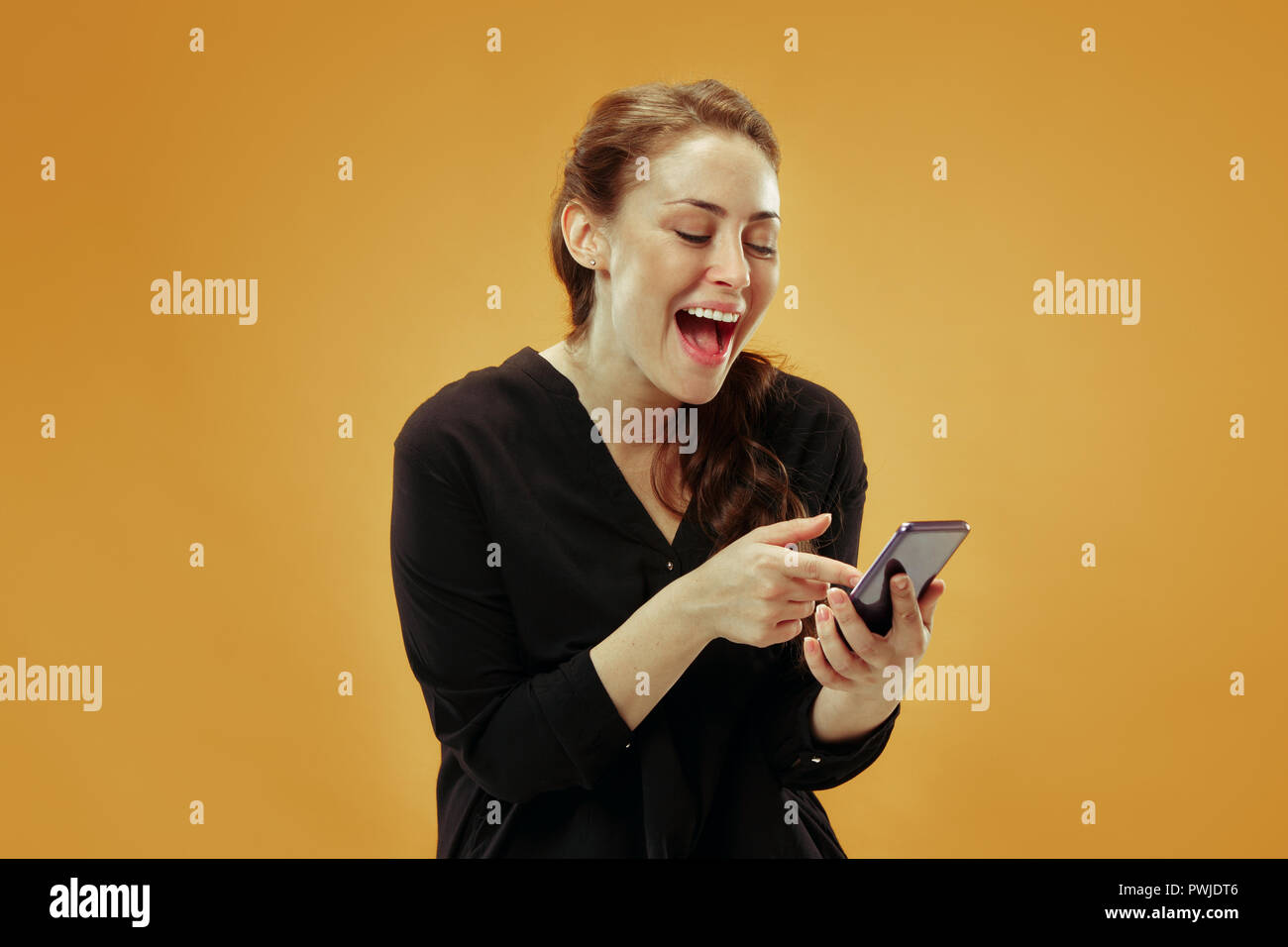 Young beautiful woman using mobile phone studio on gold color studio ...