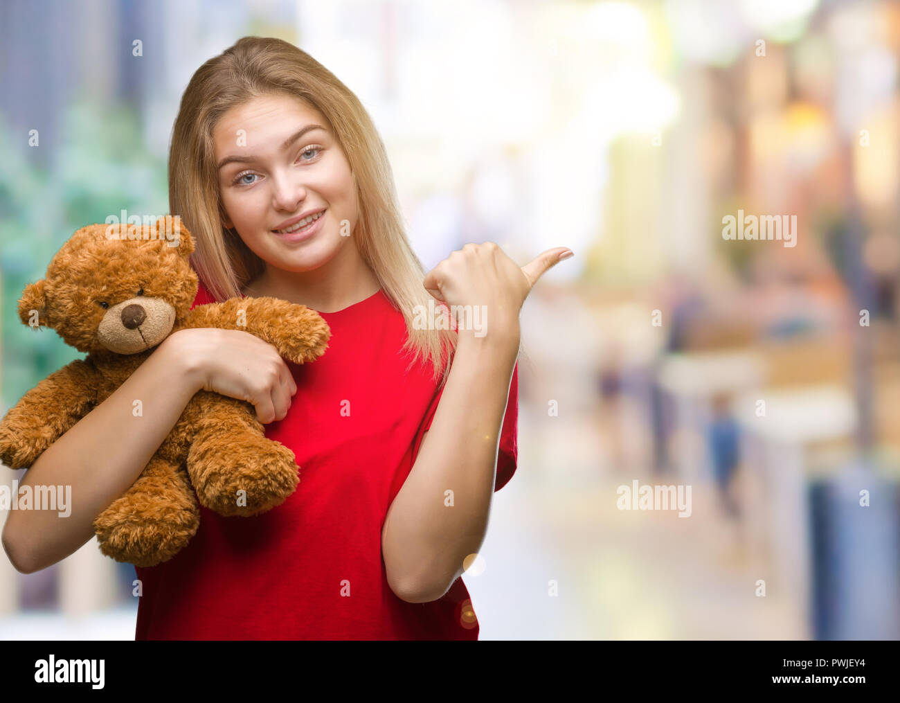 Young caucasian woman holding cute teddy bear over isolated background ...