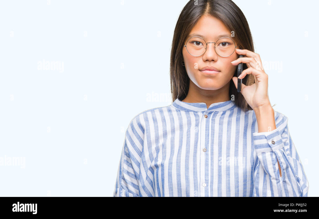Young asian woman speaking on the phone over isolated background with a ...