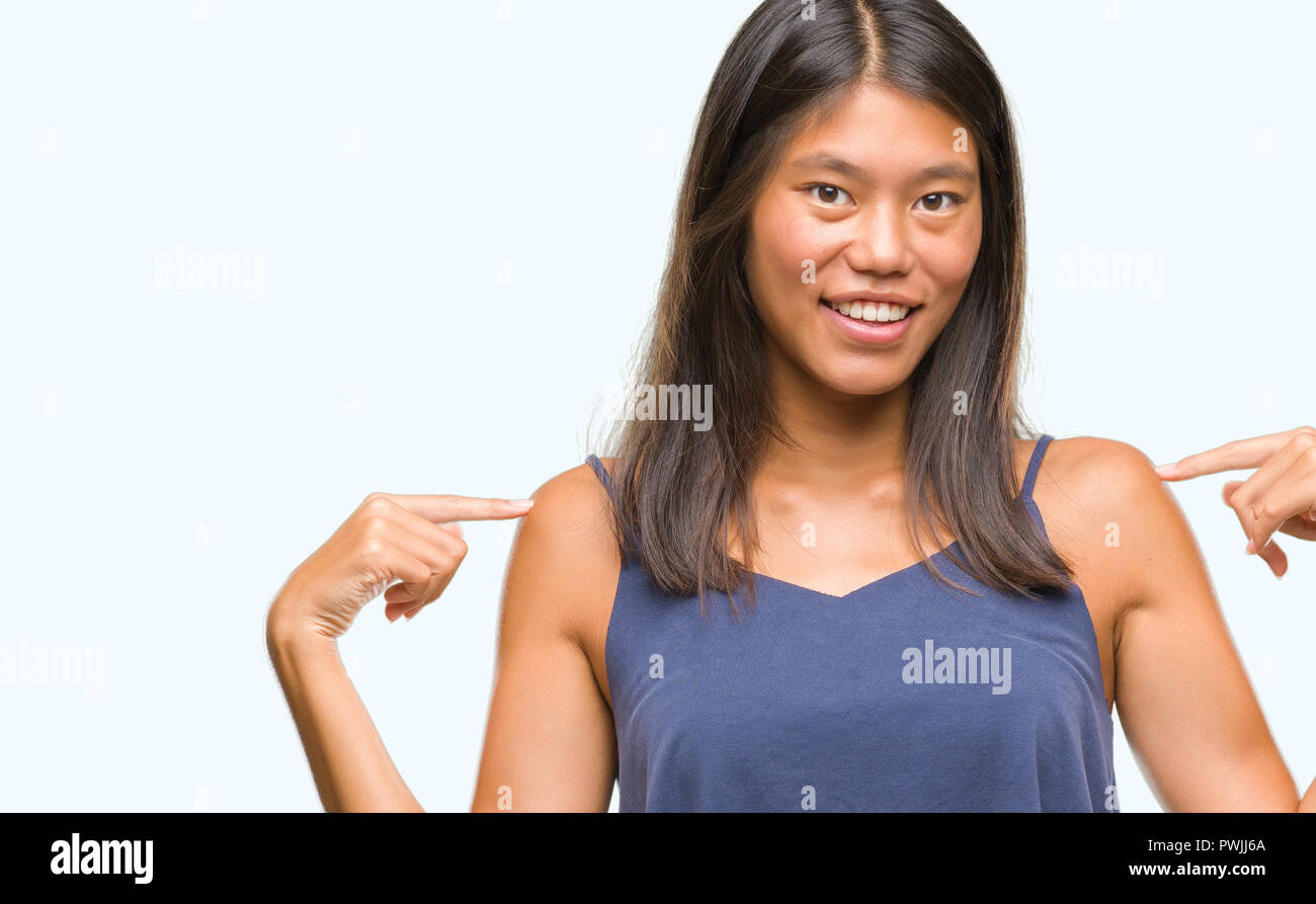 Young asian woman over isolated background looking confident with smile ...