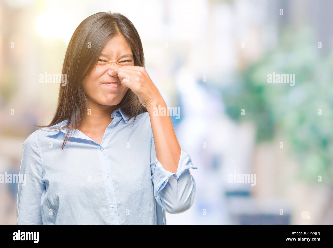 Young asian business woman over isolated background smelling something ...