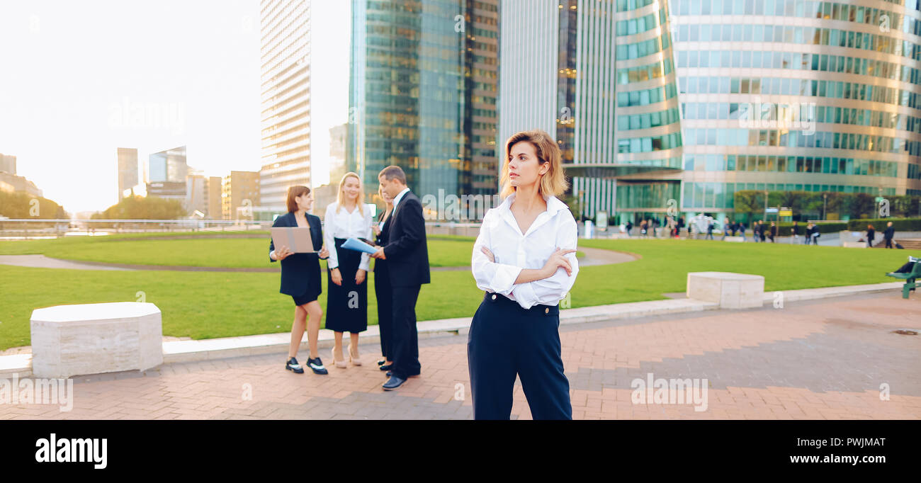 Secretary looking at camera with team members background in La D Stock ...
