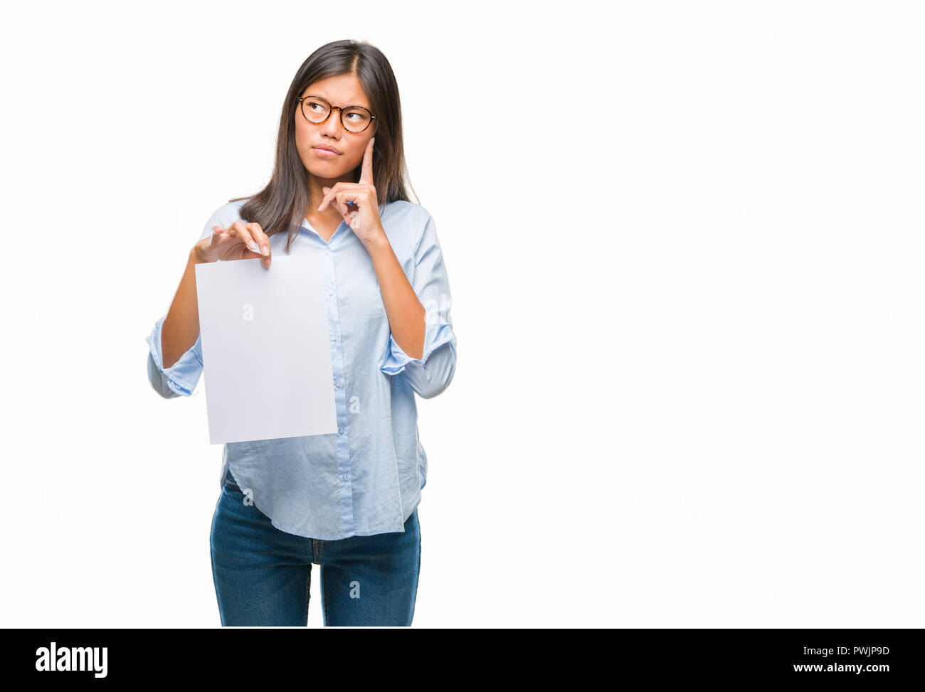 Young asian woman over isolated background holding blank paper serious ...
