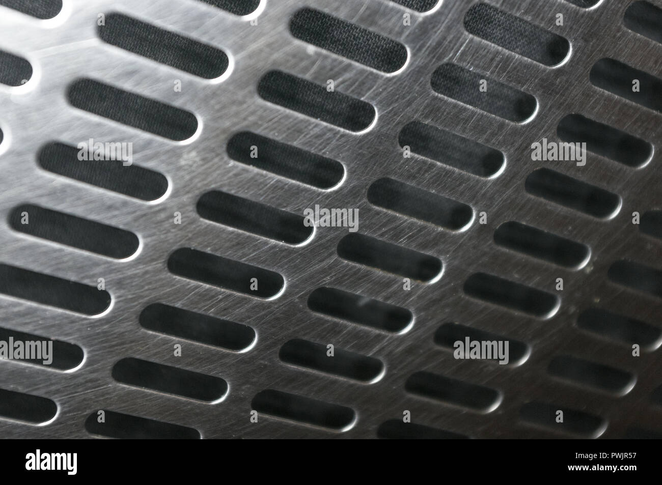 stainless steel grating with oblong holes on black background, close-up ...
